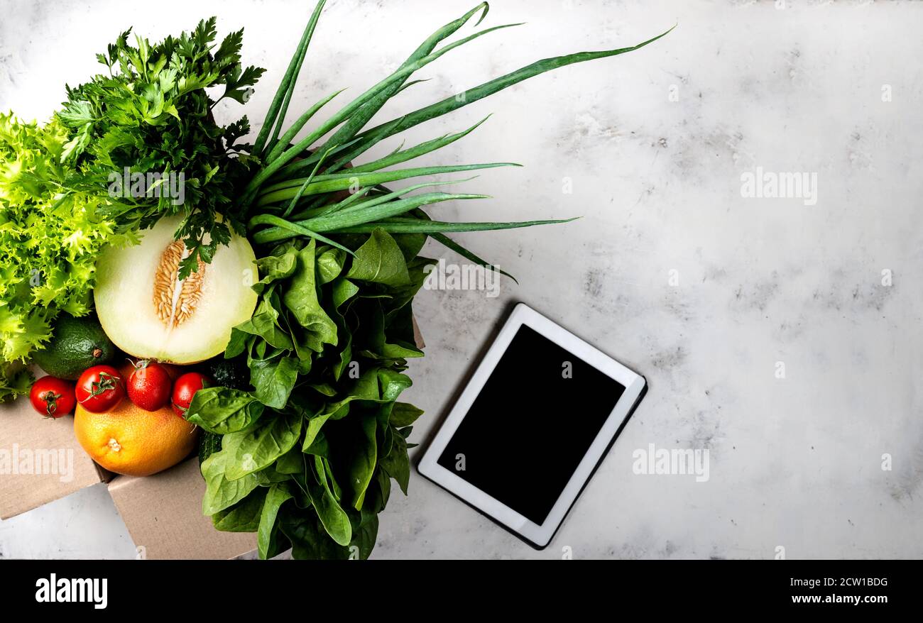 Box full of Different organic vegetables and greens and tablet computer ...