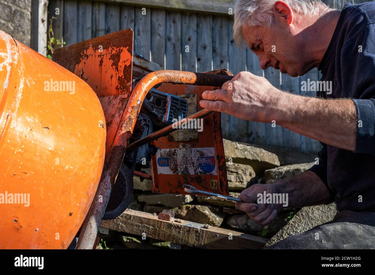 Senior Male fixing cerment mixer belt by setting tension of belt to ...