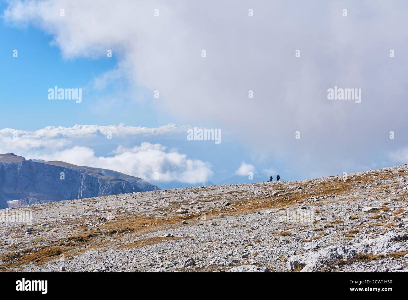 alpine plateau covered with dry grass and white stones, and a couple of ...