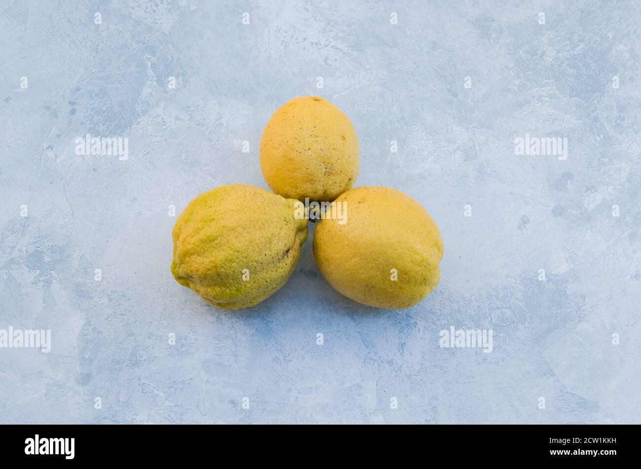 Three organic lemons on a light blue background Stock Photo - Alamy