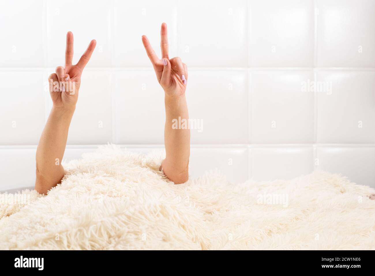Female hands show a v sign in a white bed, a wonderful start to a new ...