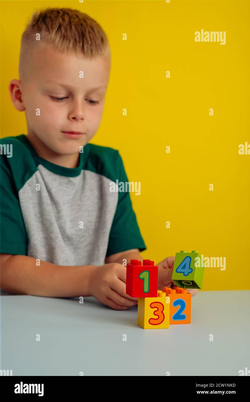 The child playing with cubes with numbers on the table.On a yellow ...