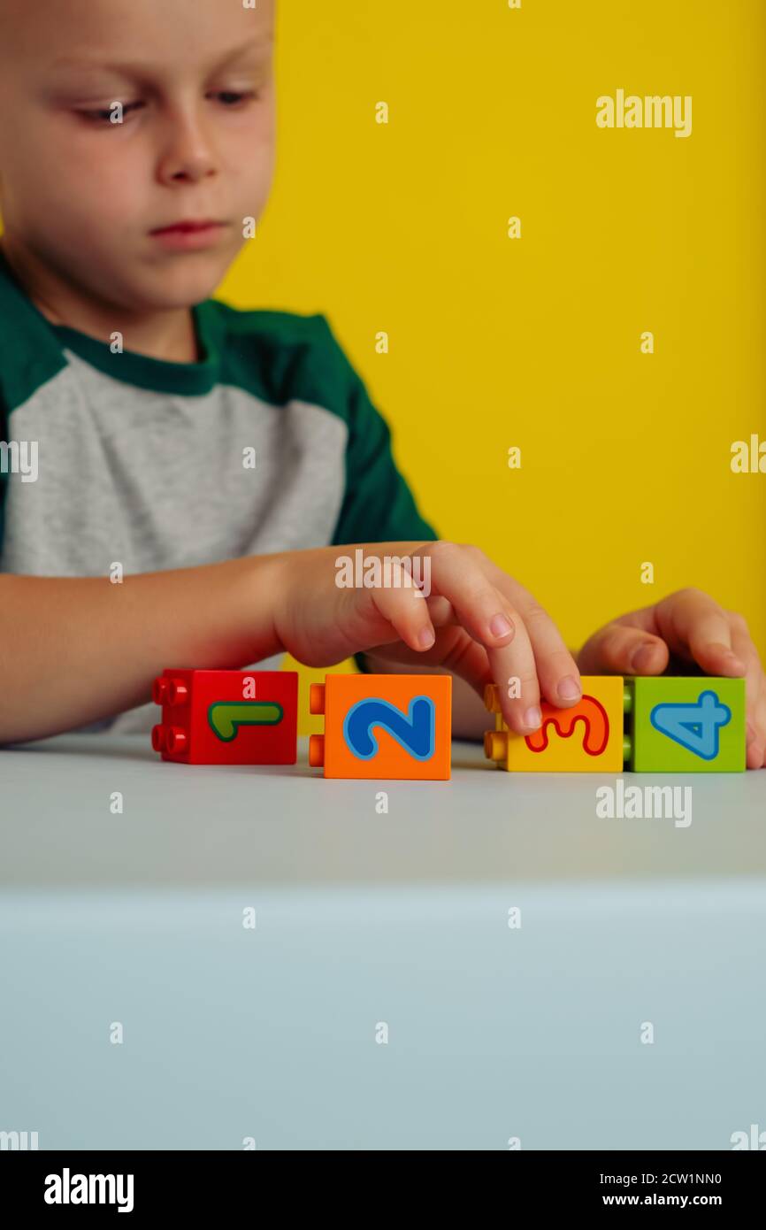 The child playing with cubes with numbers on the table.On a yellow ...