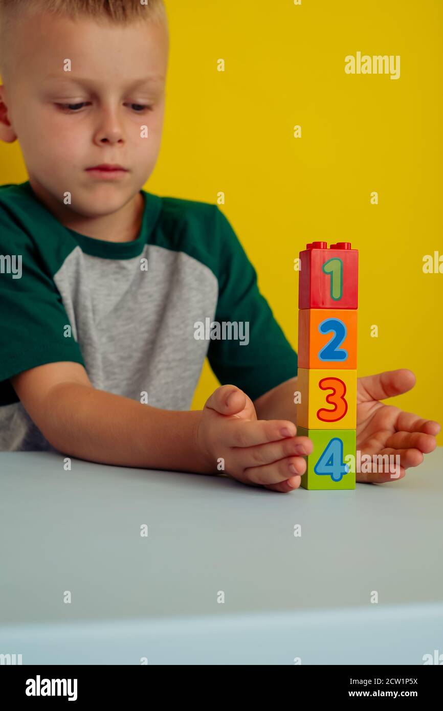 The child playing with cubes with numbers on the table.On a yellow ...