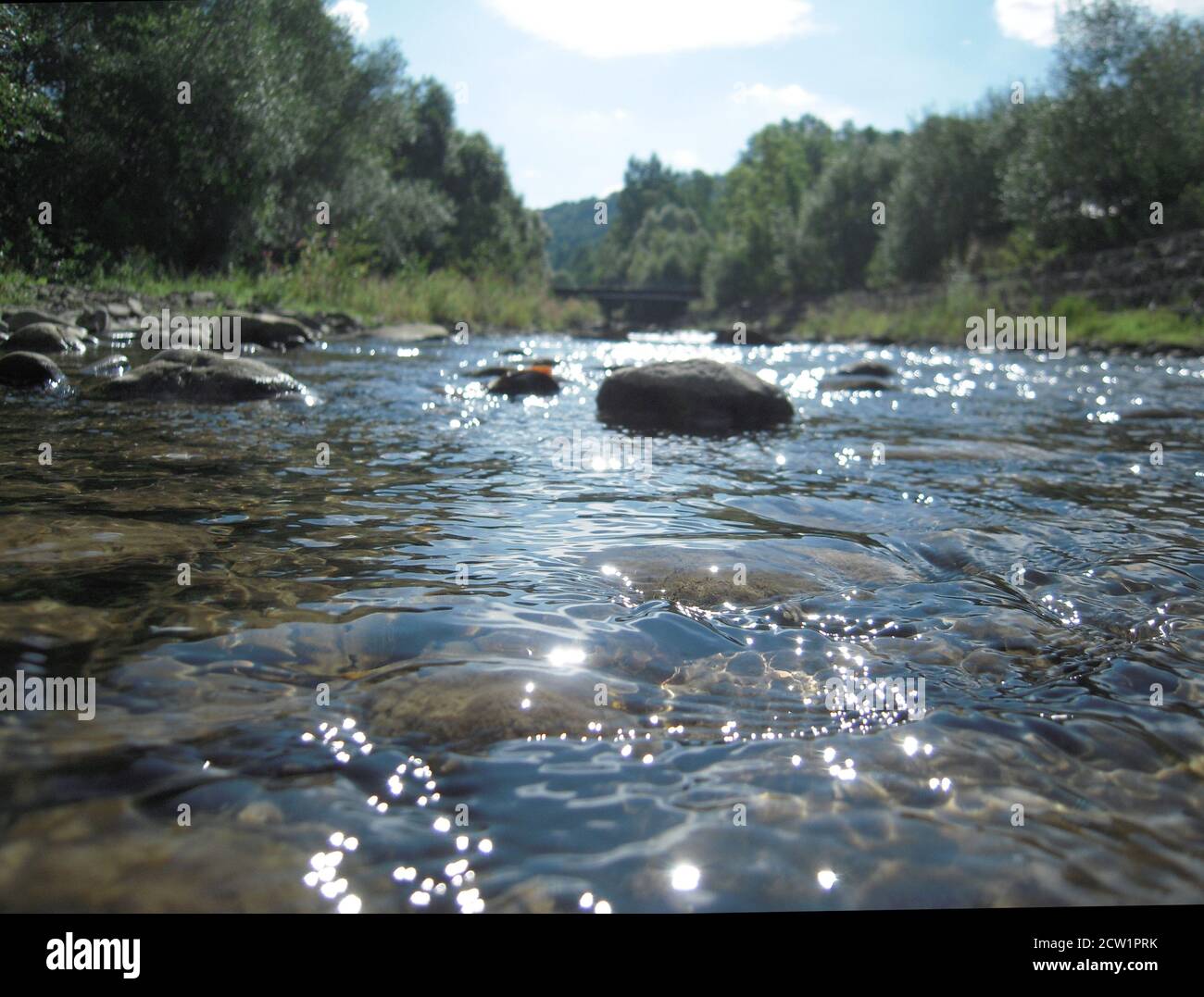 Water flowing in the mountain river. Water surface with sun reflections ...