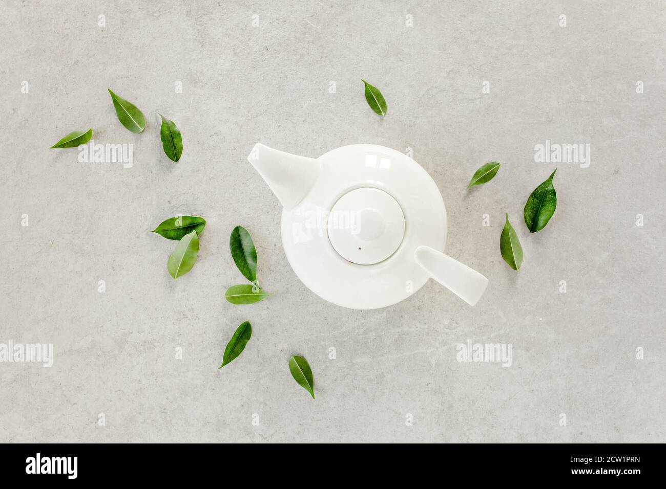 Herbal tea in a white teapot, with green tea leaves. Flat lay, top view ...
