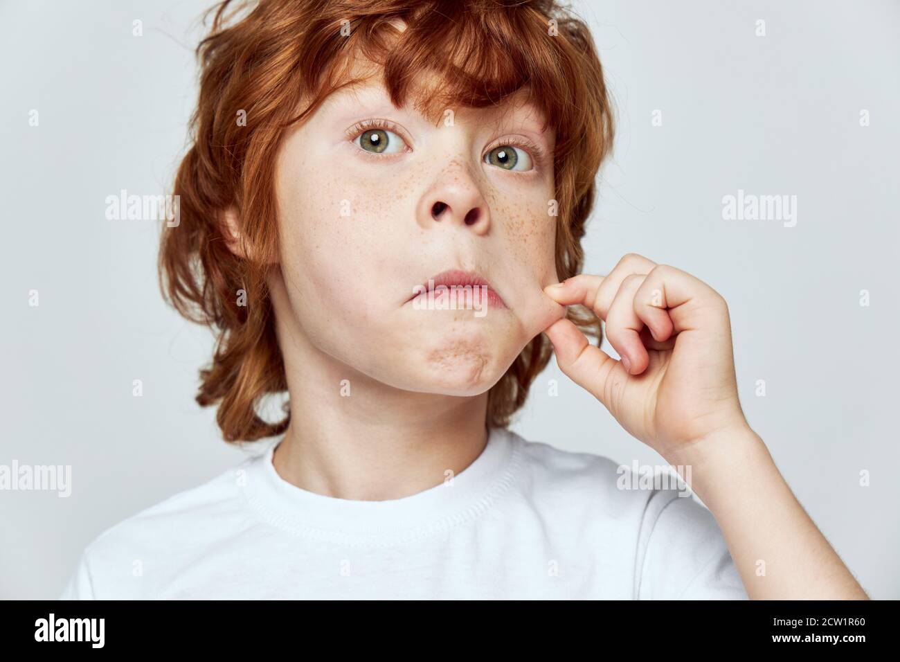 redhead boy pulls his cheeks with fingers antics close-up cropped white ...