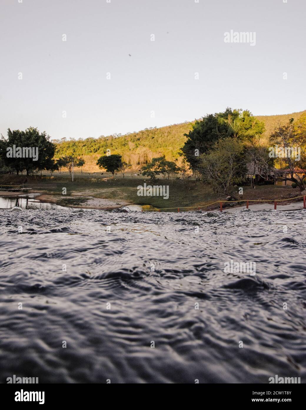 Beautiful flowing river surrounded by hills covered in greens Stock ...