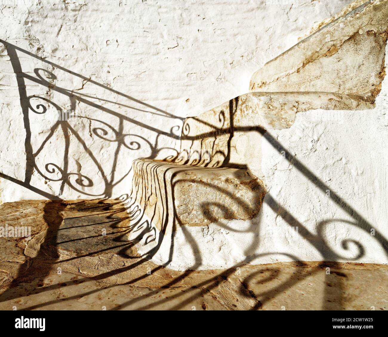 A metal railing casts a striking shadow on a staircase in front of a ...