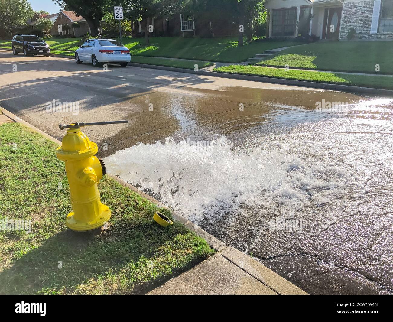 Testing yellow fire hydrant gushing water across a residential street ...