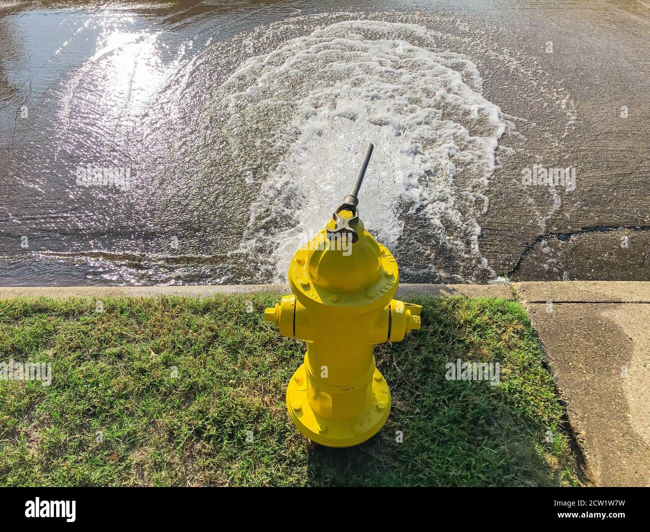 Top view yellow fire hydrant gushing water across a residential street ...