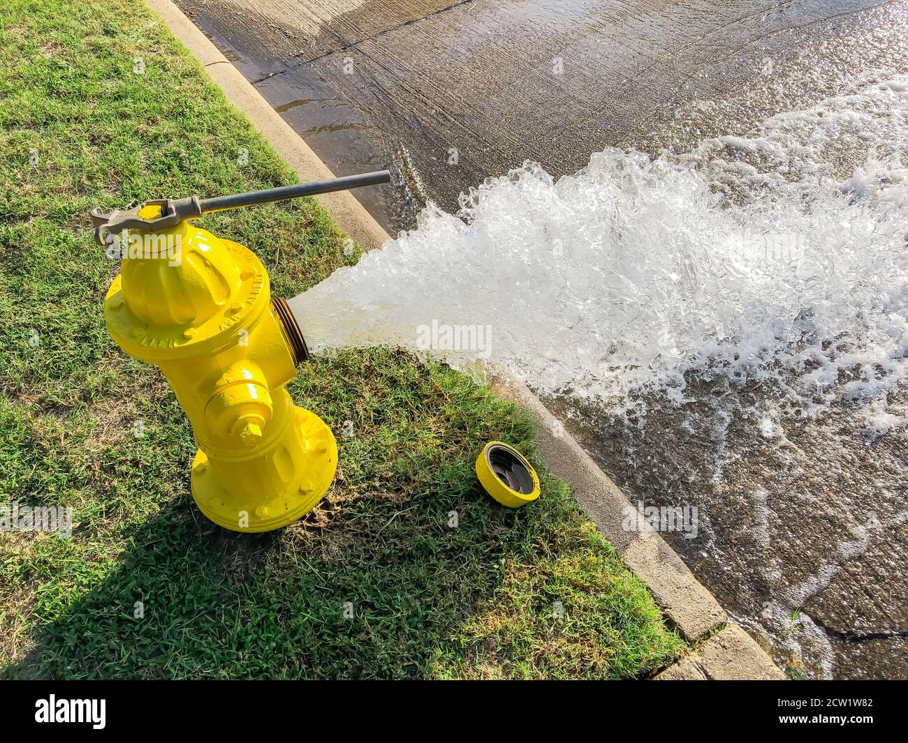 Top view yellow fire hydrant gushing water across a residential street ...