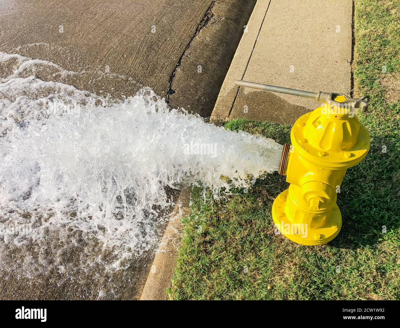 Top view yellow fire hydrant gushing water across a residential street ...
