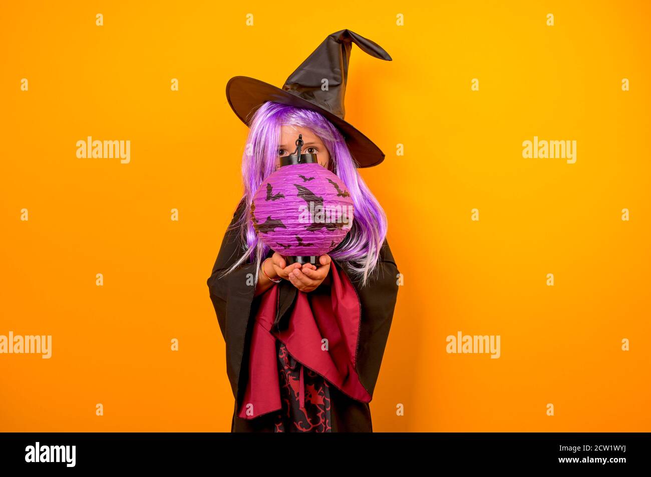 Enthusiastic little girl in a witch costume and heloin lanterns. Person ...