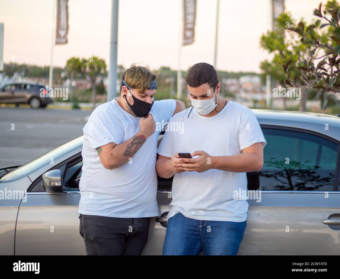Males using their phones while standing in front of a car Stock Photo ...