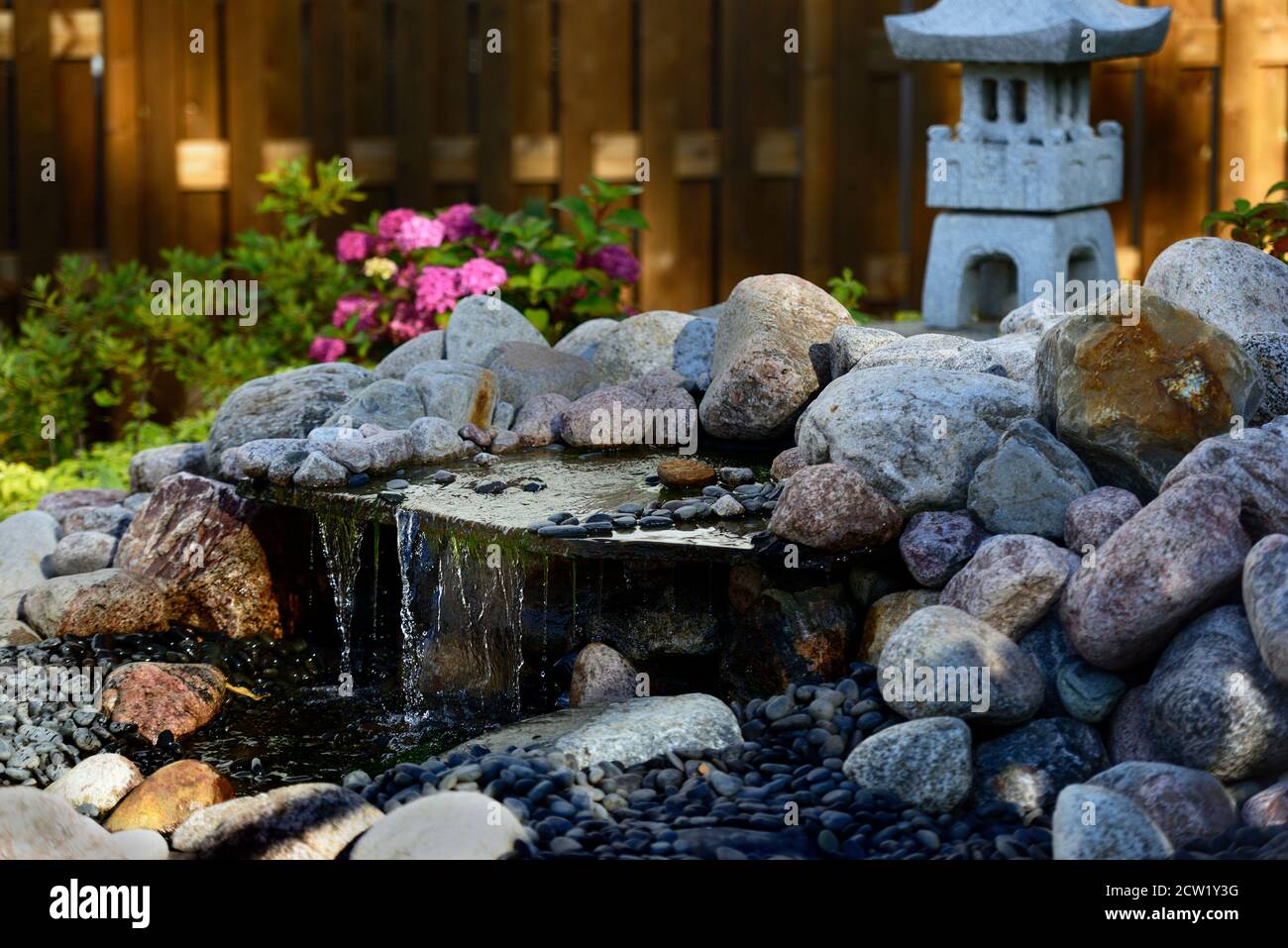 traditional Japanese garden with a stone pagoda and a small waterfall ...