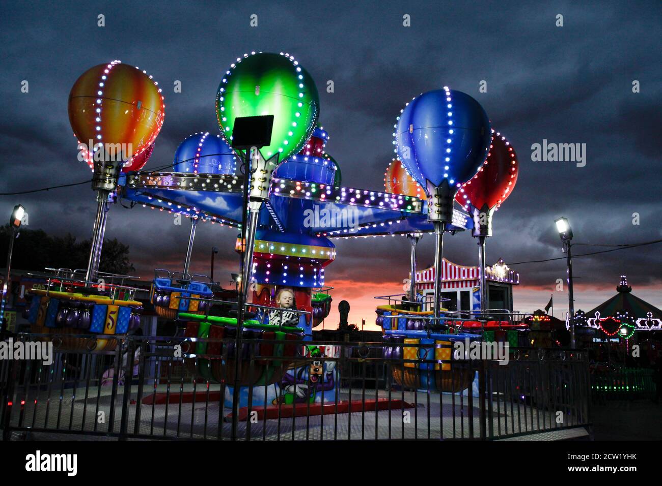Childrens amusement ride at sunset, hot air balloons, lights of the ...