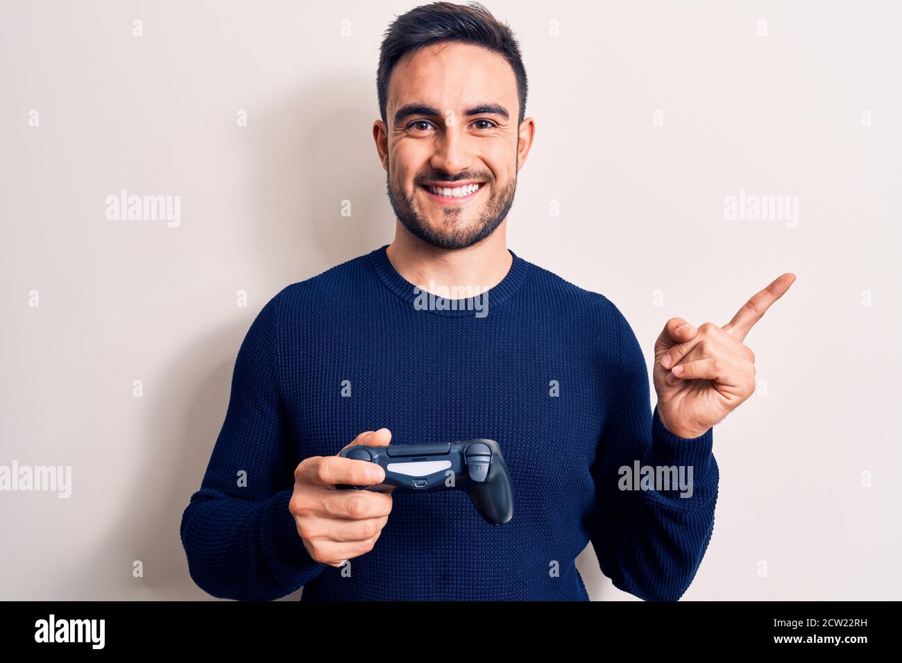 Handsome gamer man with beard playing video game using gamepad over ...