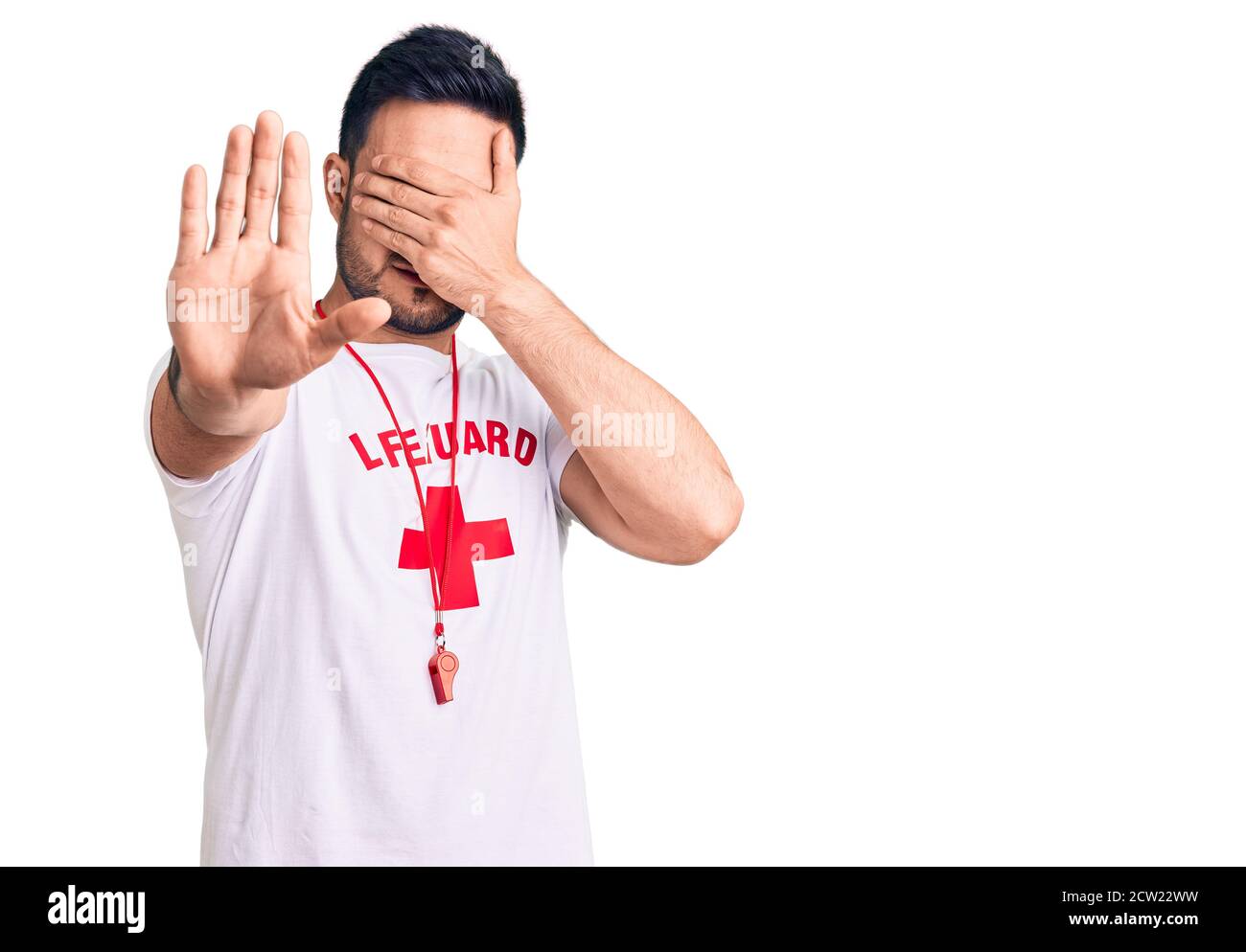 Young handsome man wearing lifeguard uniform covering eyes with hands ...