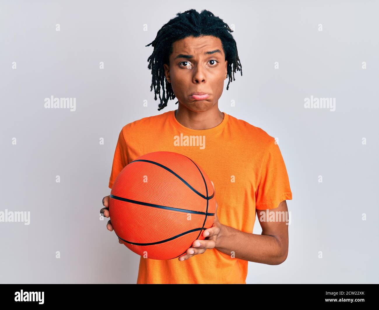 Young african american man holding basketball ball depressed and worry ...