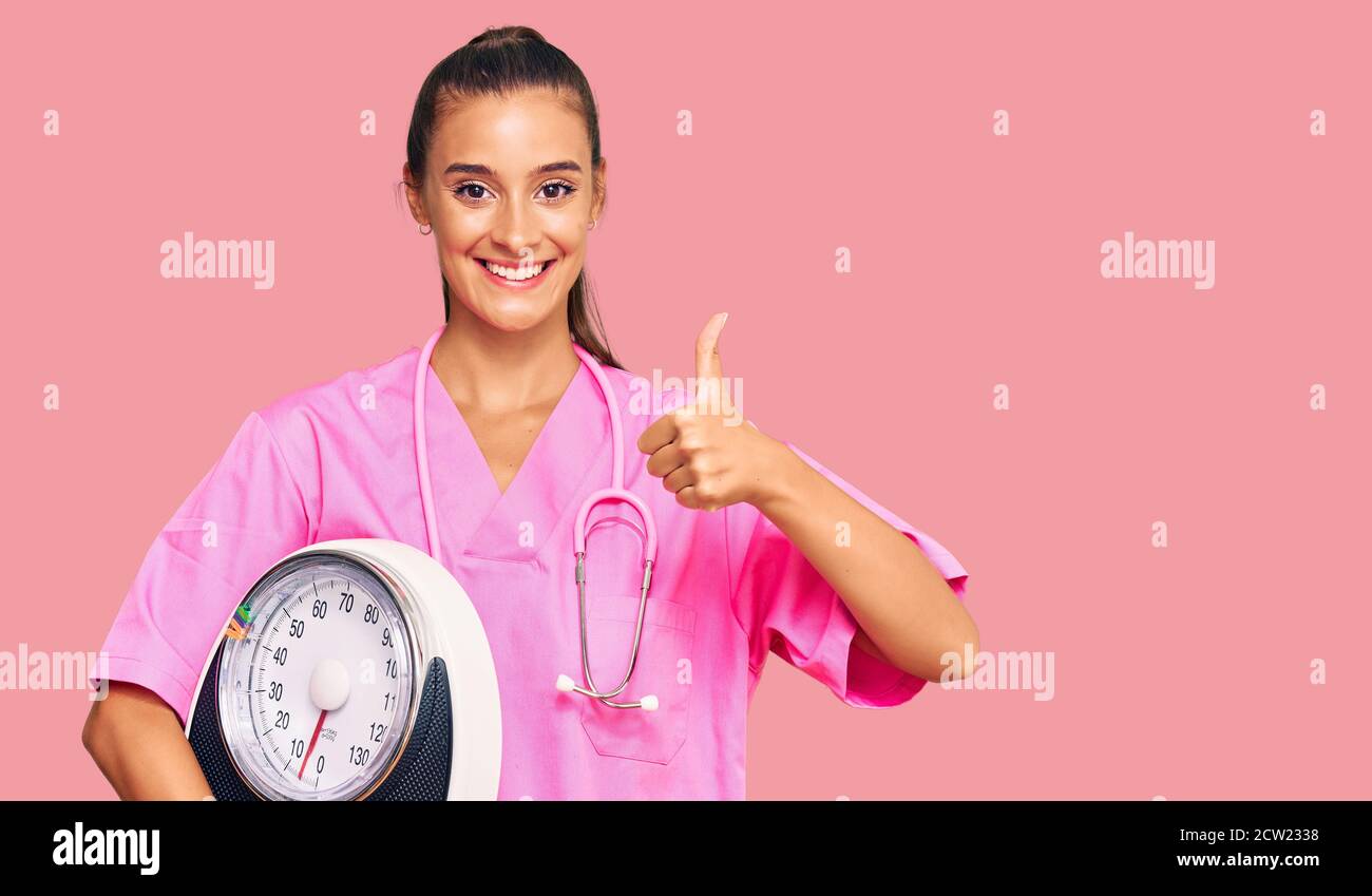 Young hispanic woman as nutritionist doctor holding weighing machine ...