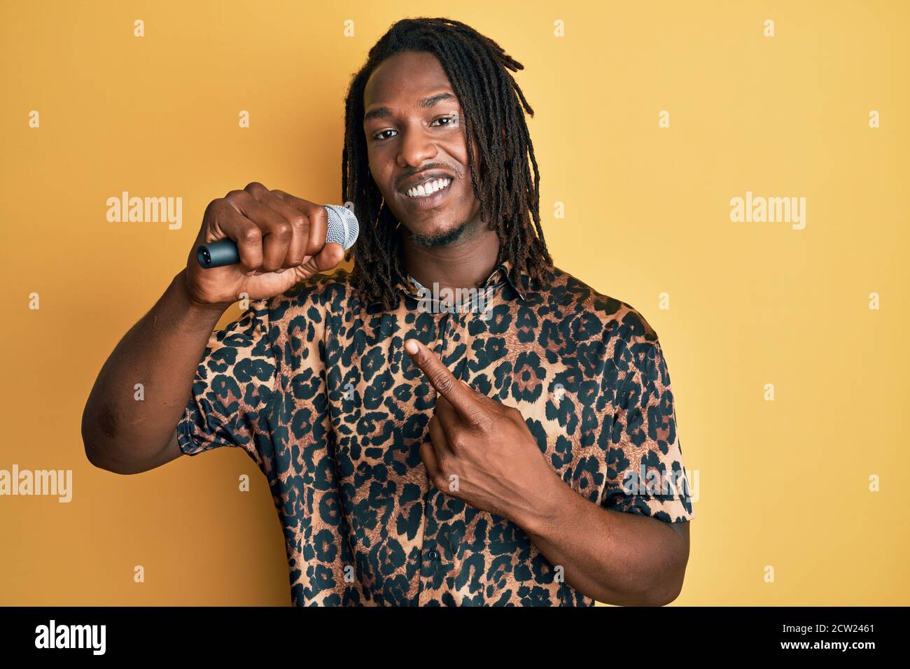 African american man with braids singing song using microphone smiling ...