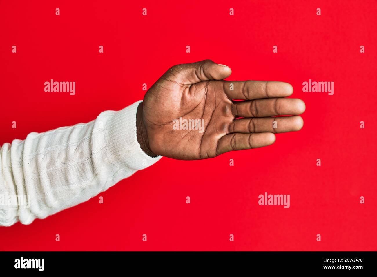Arm and hand of african american black young man over red isolated ...