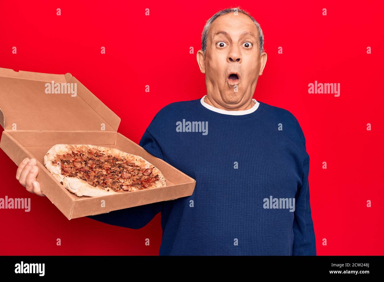 Senior man with grey hair holding delivery cardboard of italian pizza ...
