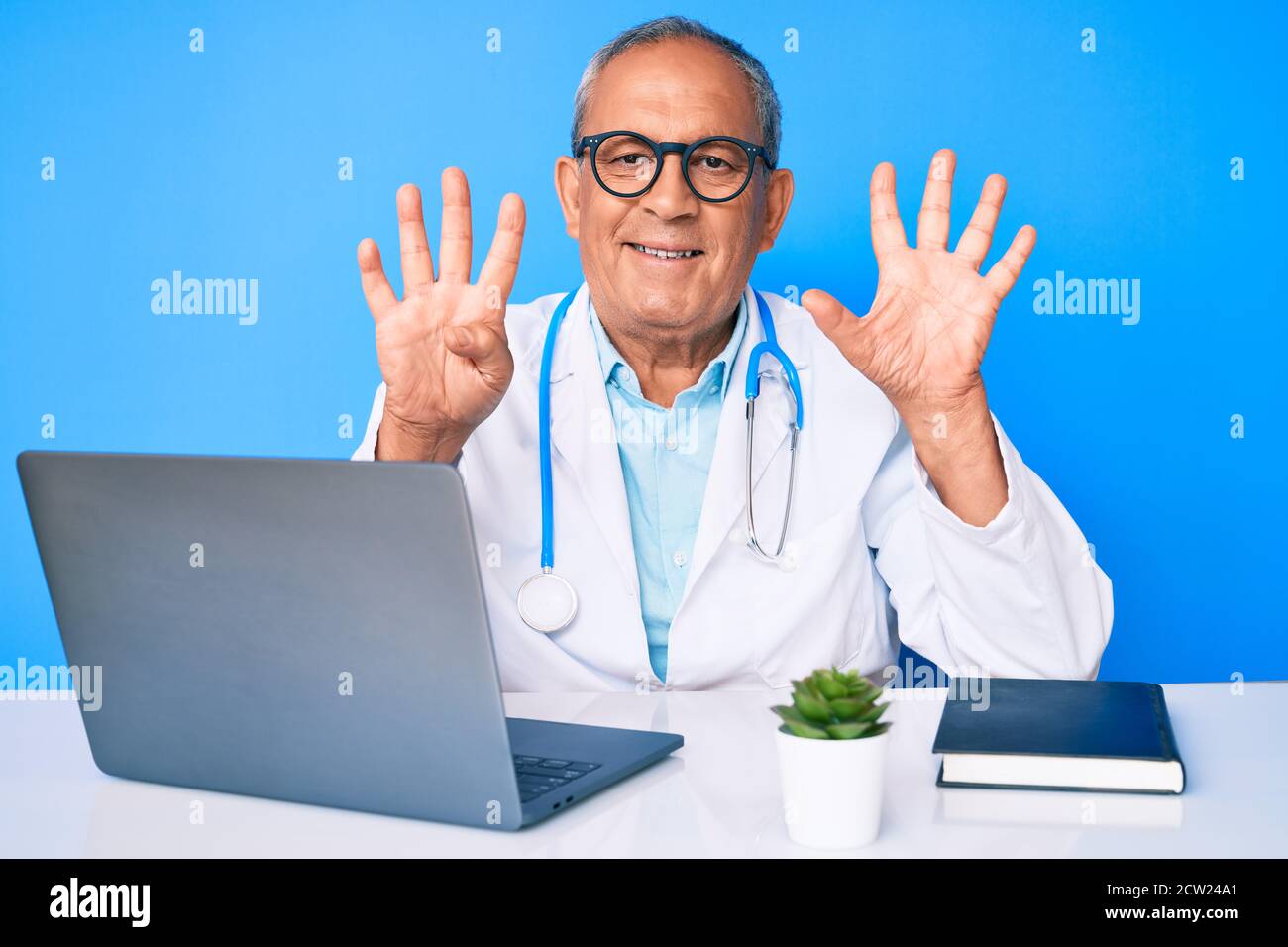 Senior handsome man with gray hair wearing doctor uniform working using ...