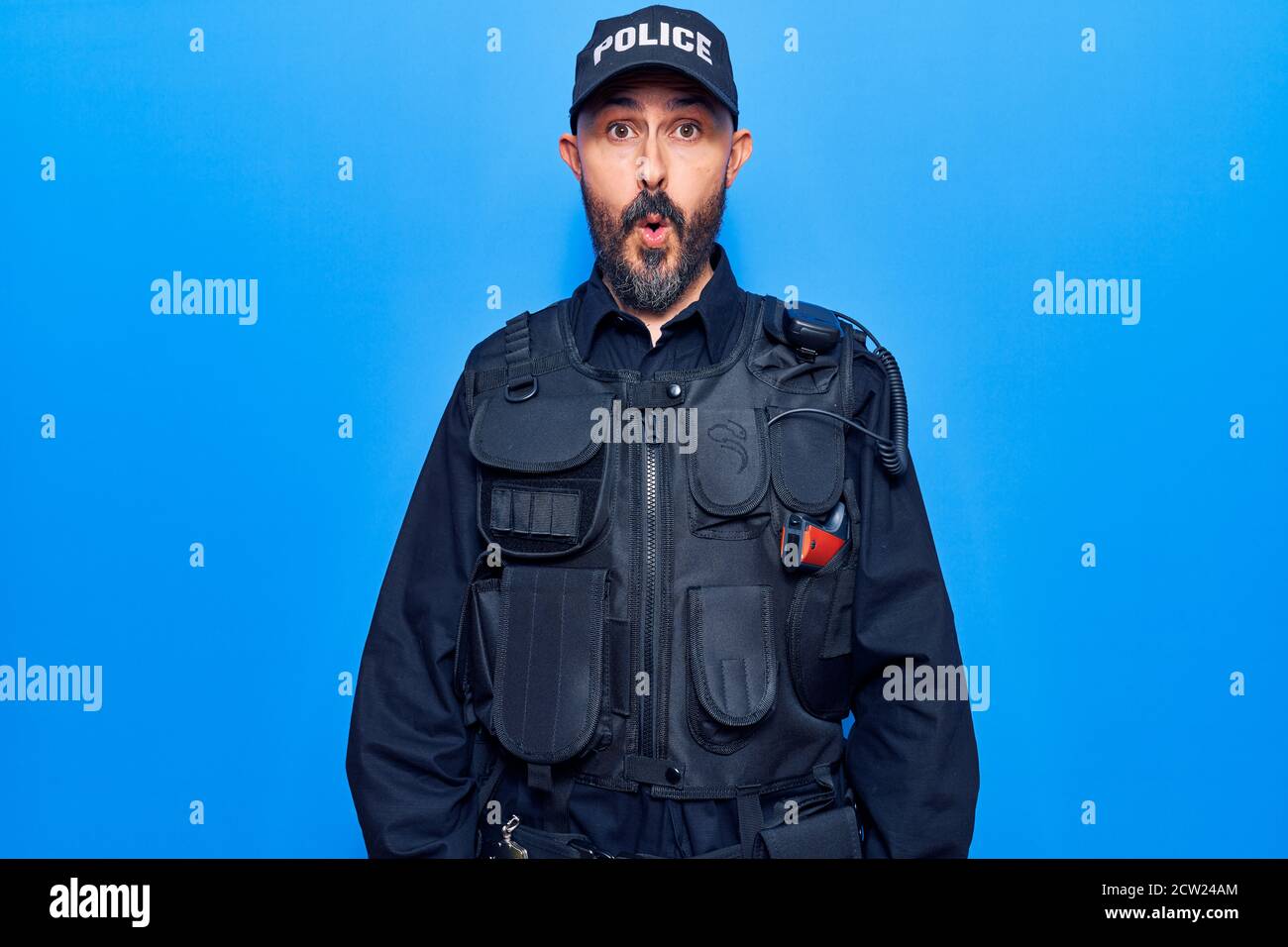 Young handsome man wearing police uniform scared and amazed with open ...