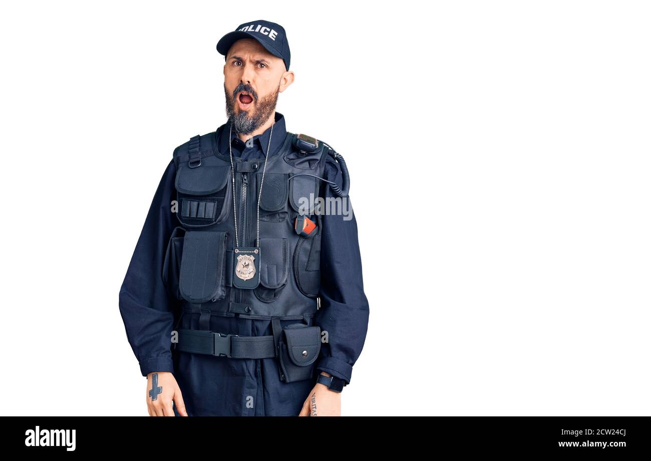 Young handsome man wearing police uniform in shock face, looking ...