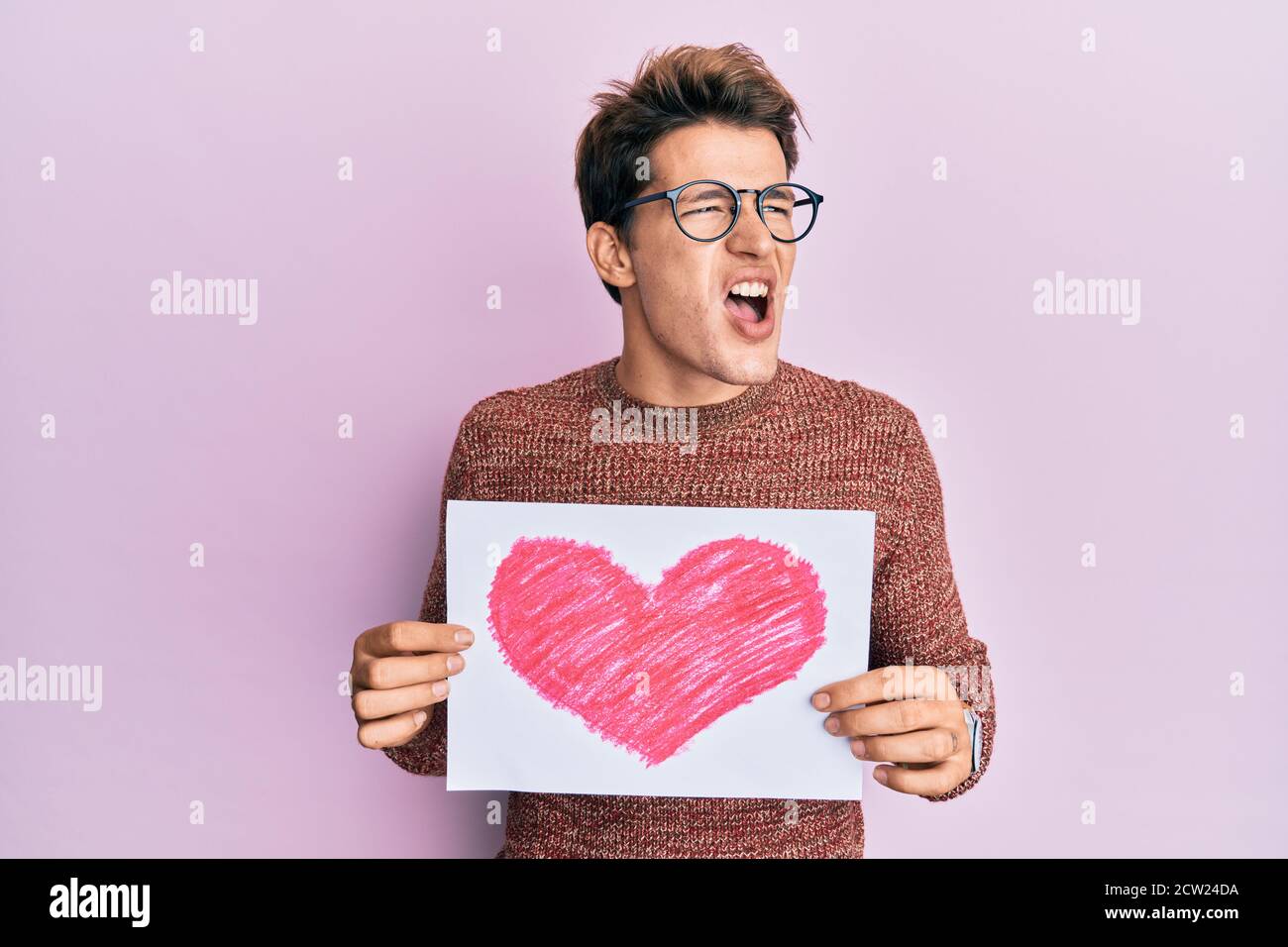Handsome caucasian man holding heart draw angry and mad screaming ...