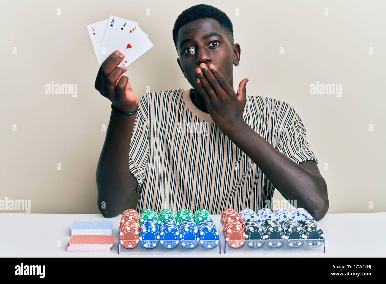 Young african american man playing poker holding cards covering mouth ...
