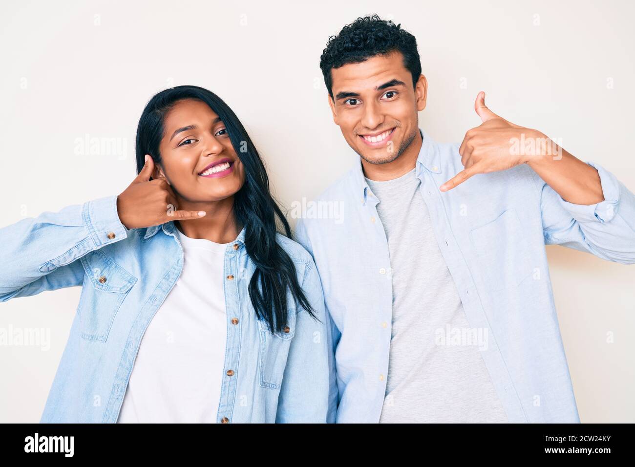 Beautiful latin young couple wearing casual clothes smiling doing phone ...