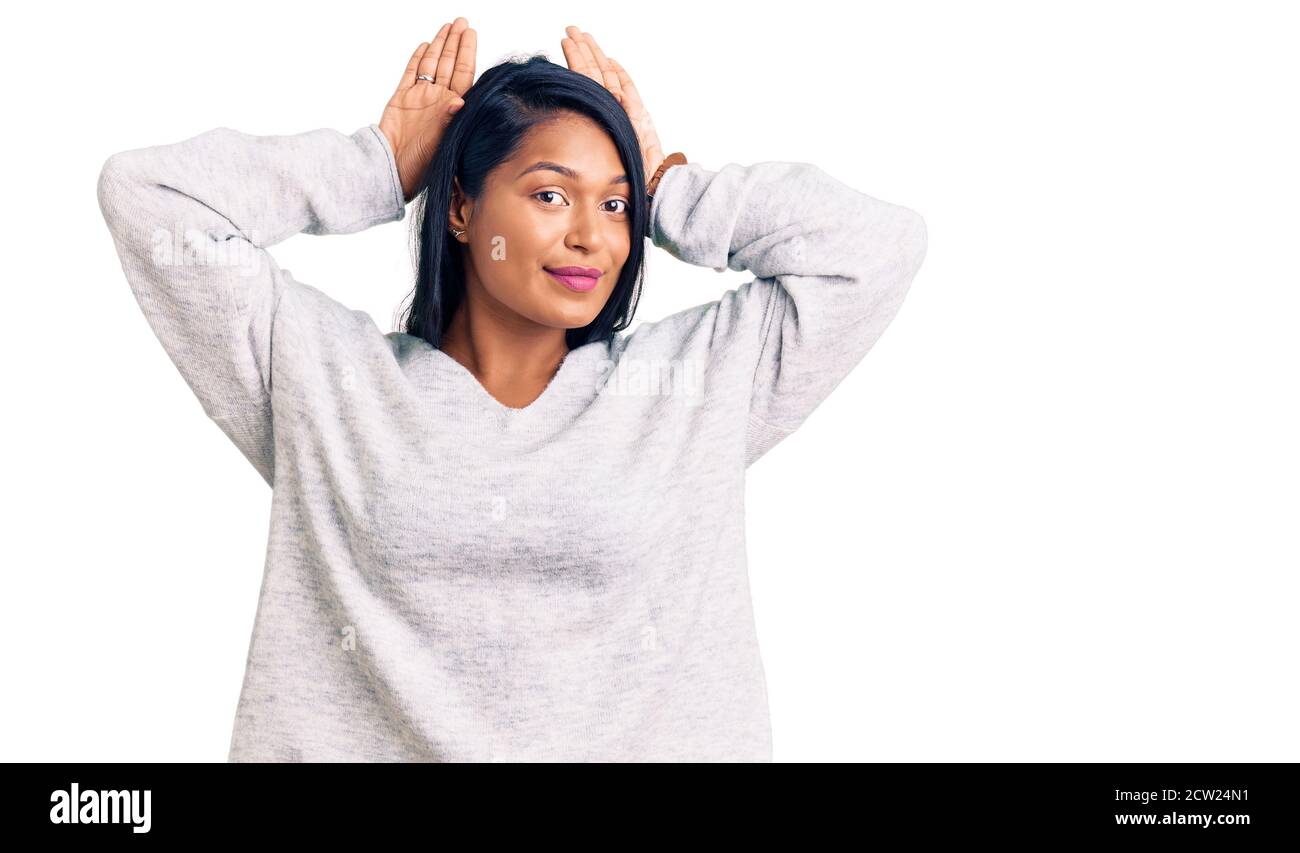 Hispanic woman with long hair wearing casual clothes doing bunny ears ...