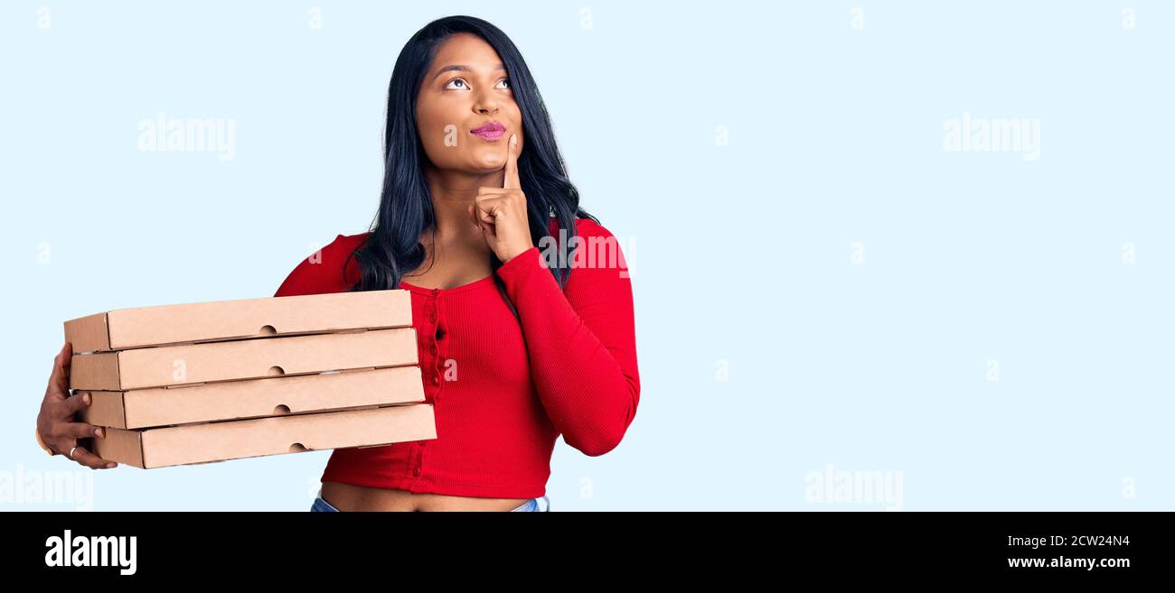 Hispanic woman with long hair holding delivery pizza box serious face ...