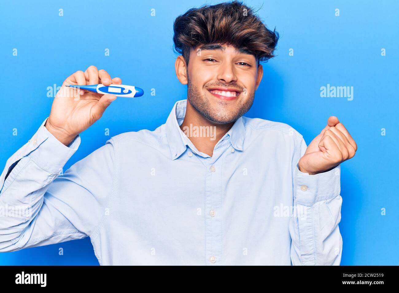 Young hispanic man holding thermometer screaming proud, celebrating ...