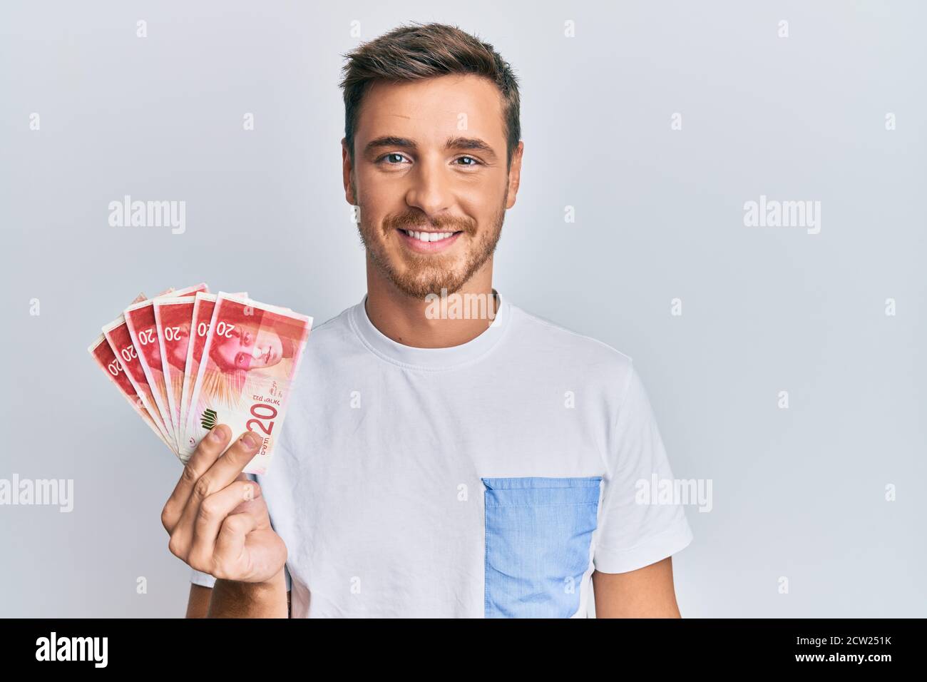 Handsome caucasian man holding israel shekels looking positive and ...