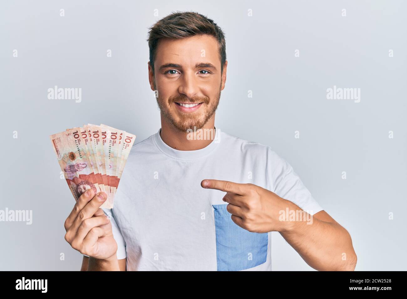 Handsome caucasian man holding 10 colombian pesos banknotes smiling ...