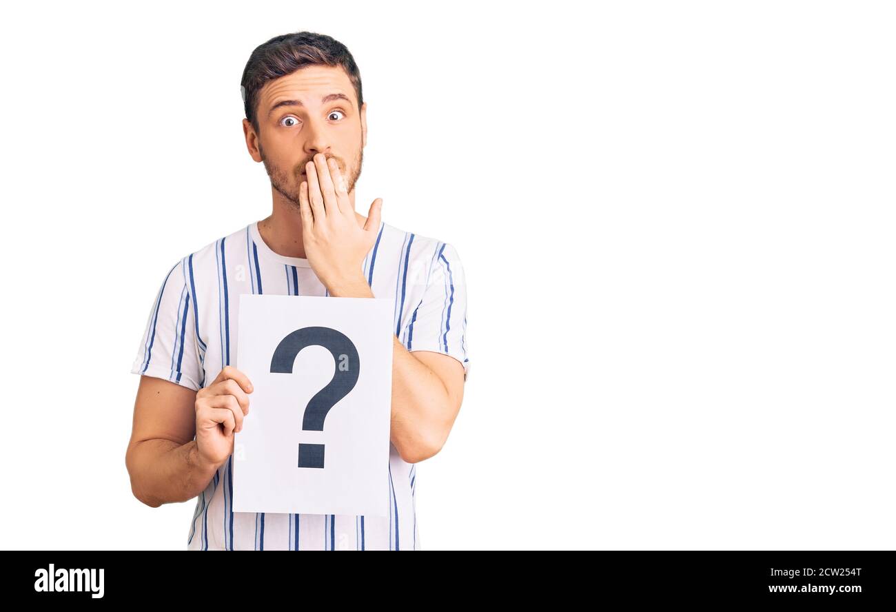 Handsome young man with bear holding question mark covering mouth with ...