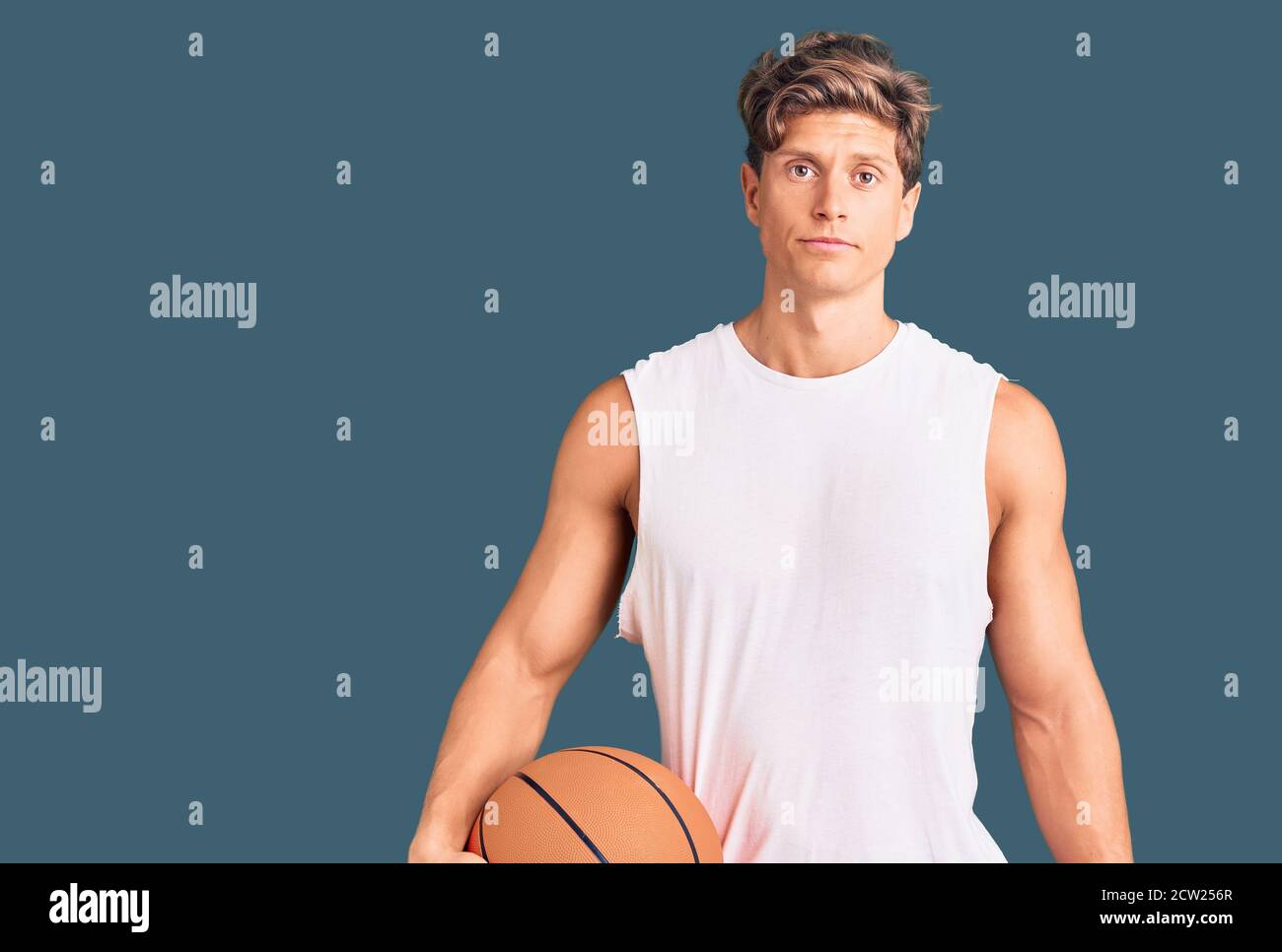 Young handsome man holding basketball ball thinking attitude and sober ...