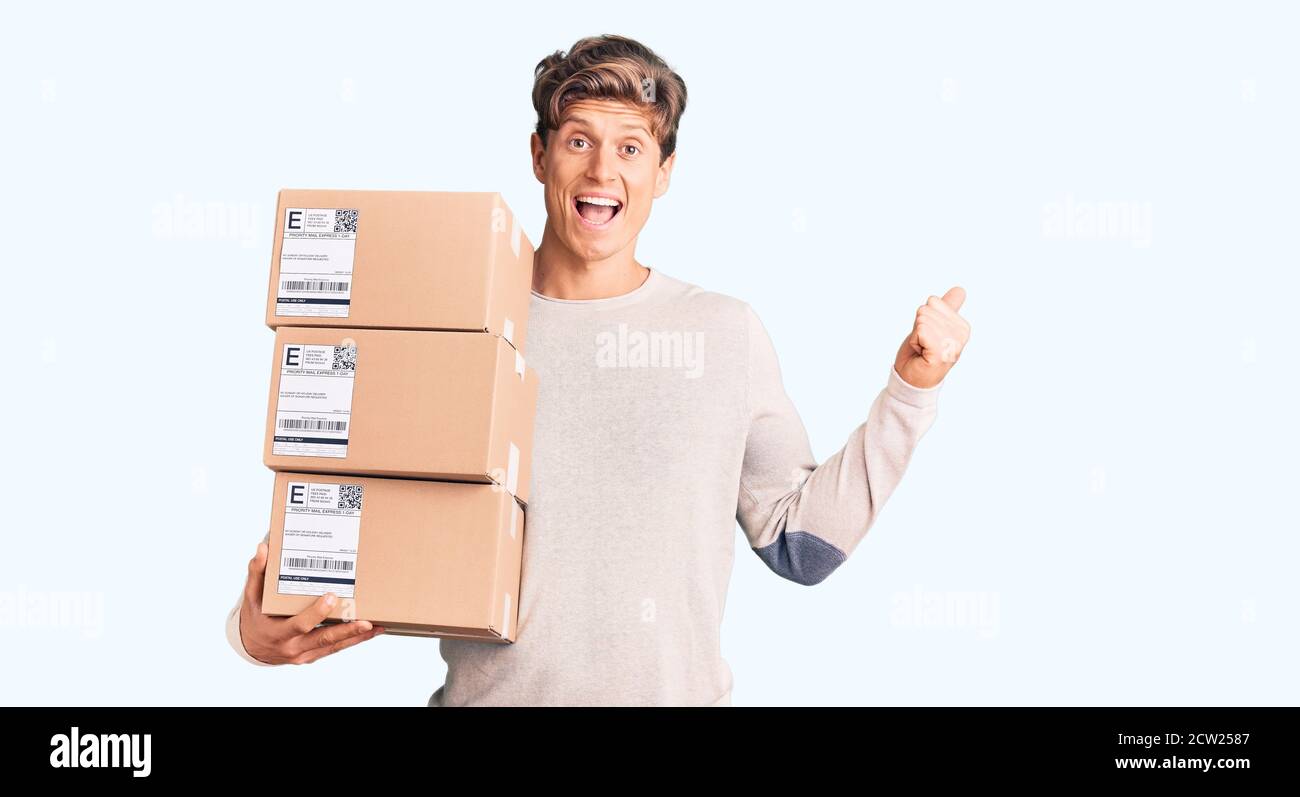 Young handsome man holding delivery package screaming proud ...