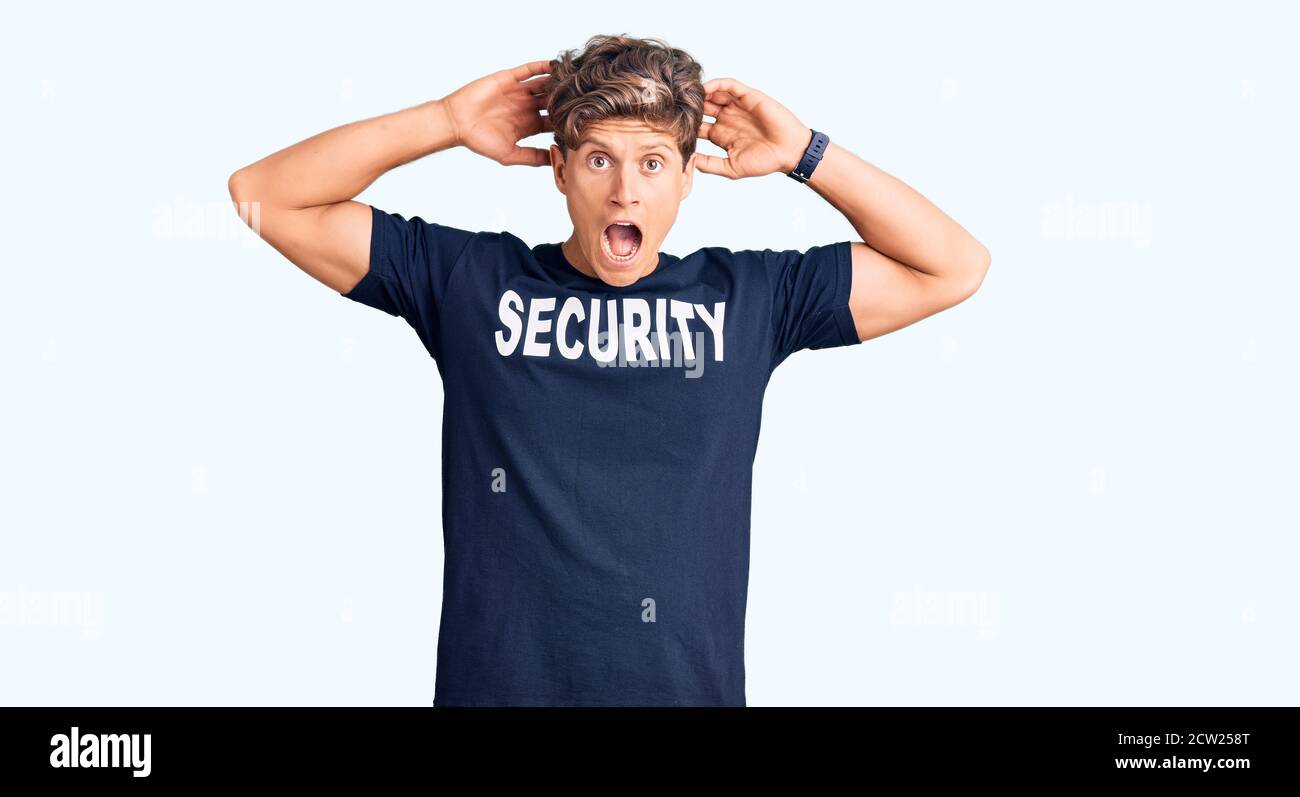 Young handsome man wearing security t shirt crazy and scared with hands ...