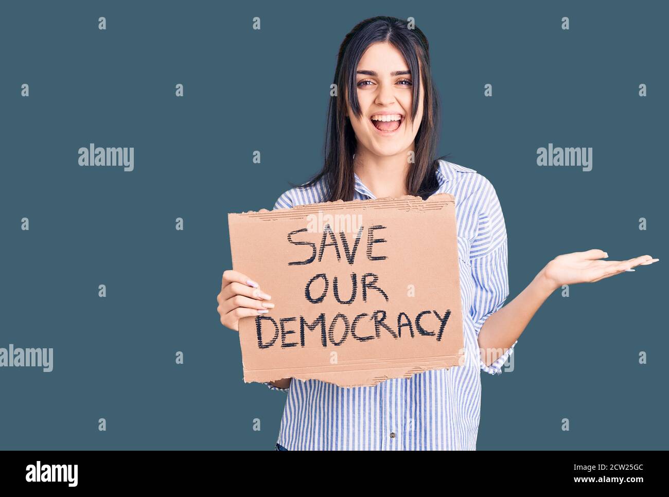 Young beautiful girl holding save our democracy cardboard banner ...
