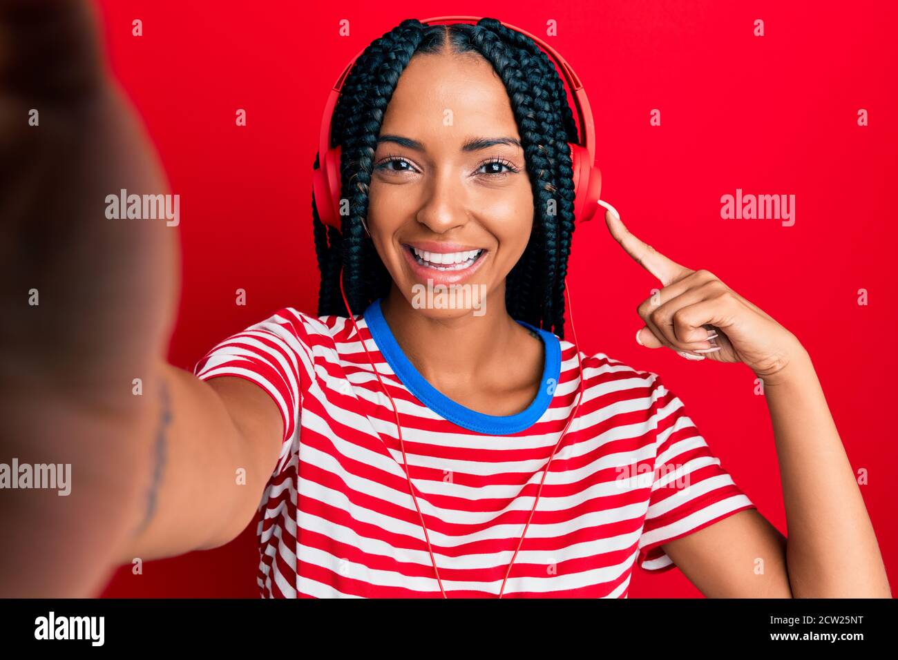 Beautiful hispanic woman taking a selfie photo wearing headphones ...