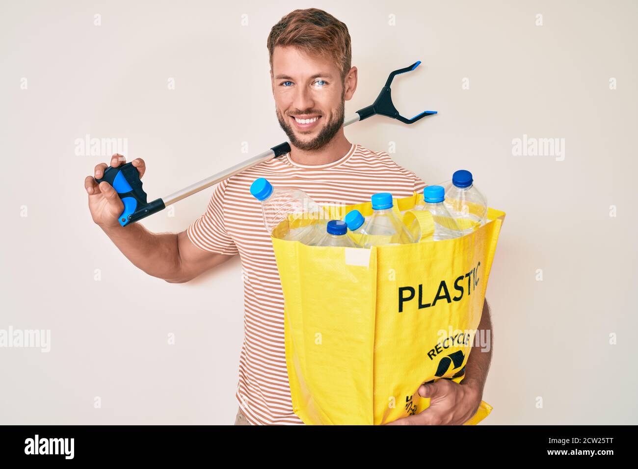 Young caucasian man holding recycling bag with plastic bottles and ...