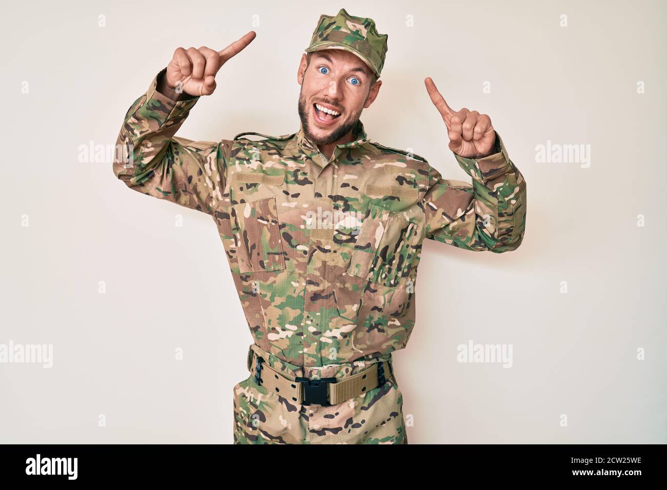 Young caucasian man wearing camouflage army uniform smiling amazed and ...