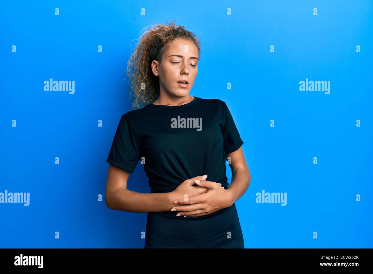 Beautiful caucasian teenager girl wearing black sportswear with hand on ...