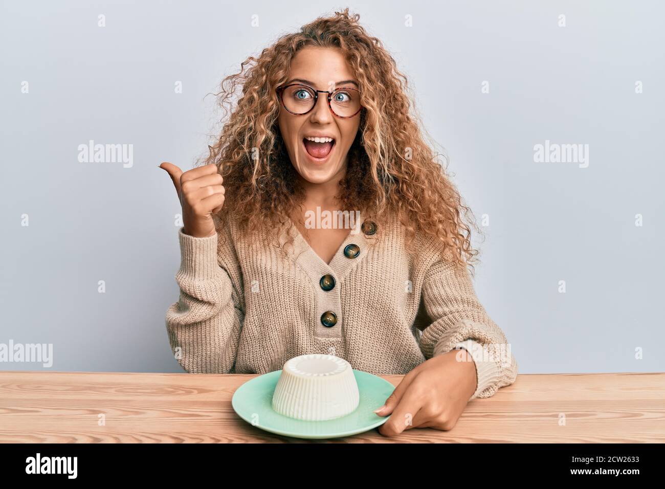 Beautiful caucasian teenager girl eating fresh white cheese pointing ...