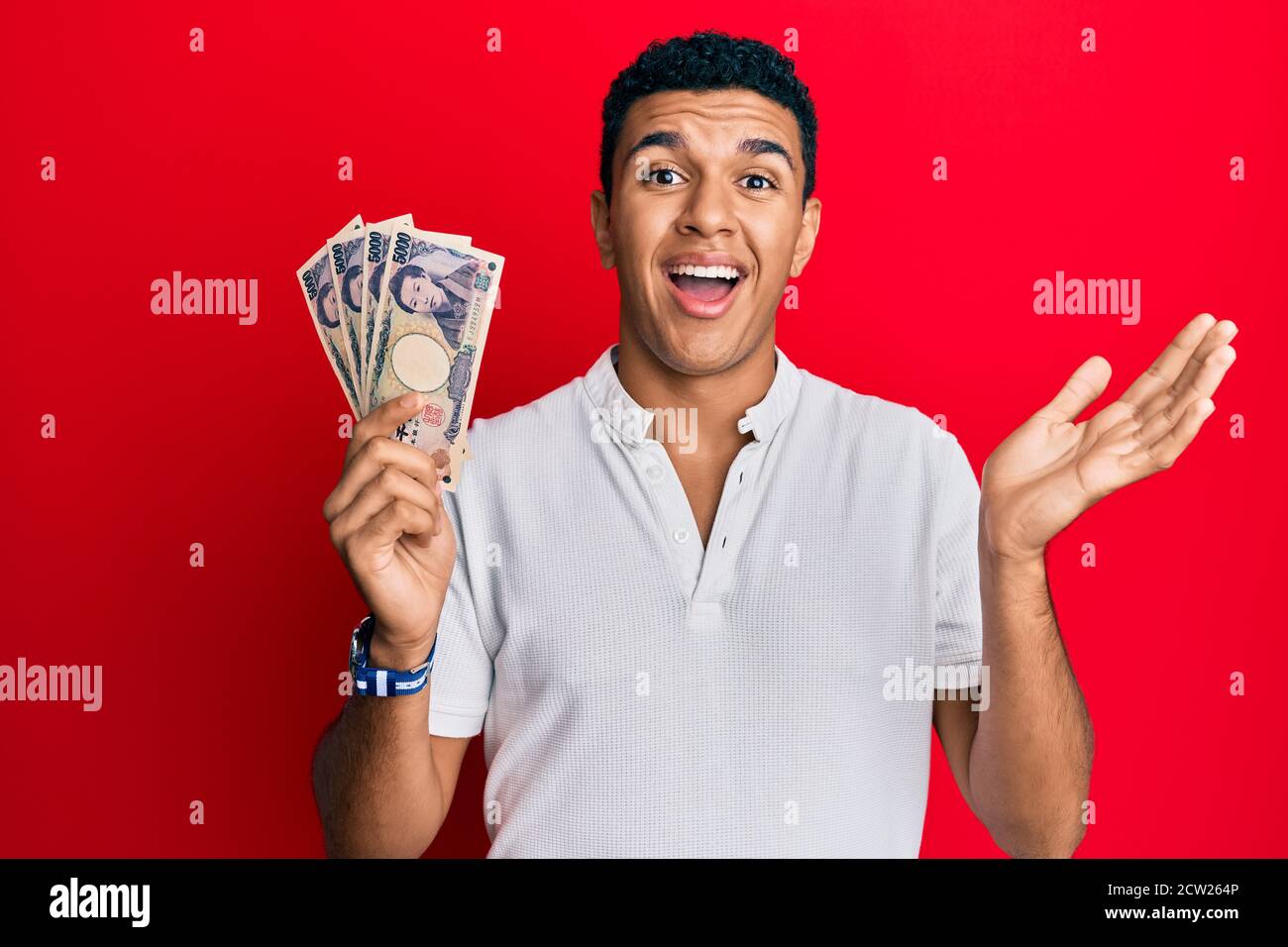 Young arab man holding japanese yen banknotes celebrating achievement ...
